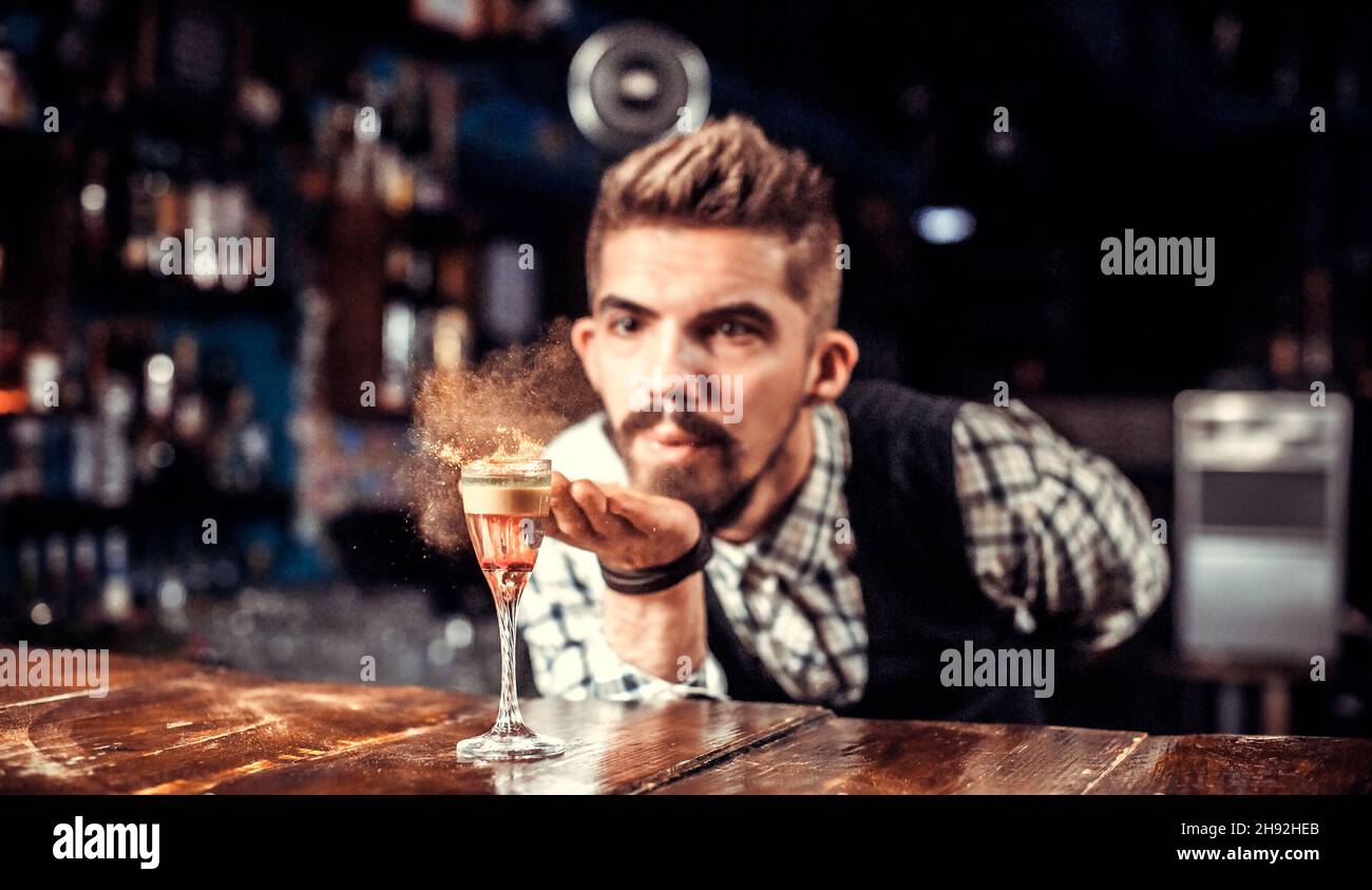 Charismatic bartender pouring fresh alcoholic drink into the glasses at the nightclub Stock ...