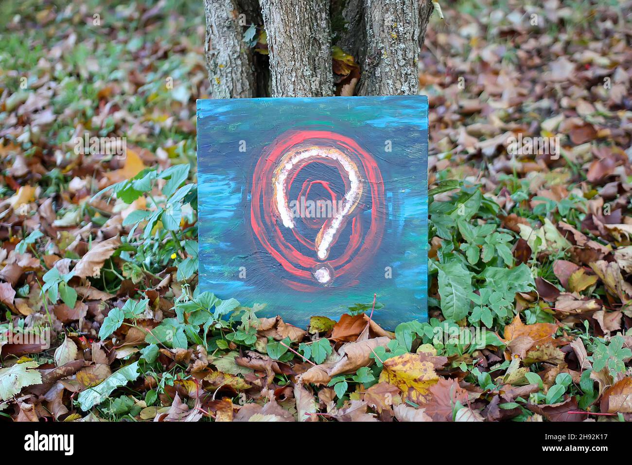 Easel with paints and painting with question mark on canvas in autumn ...