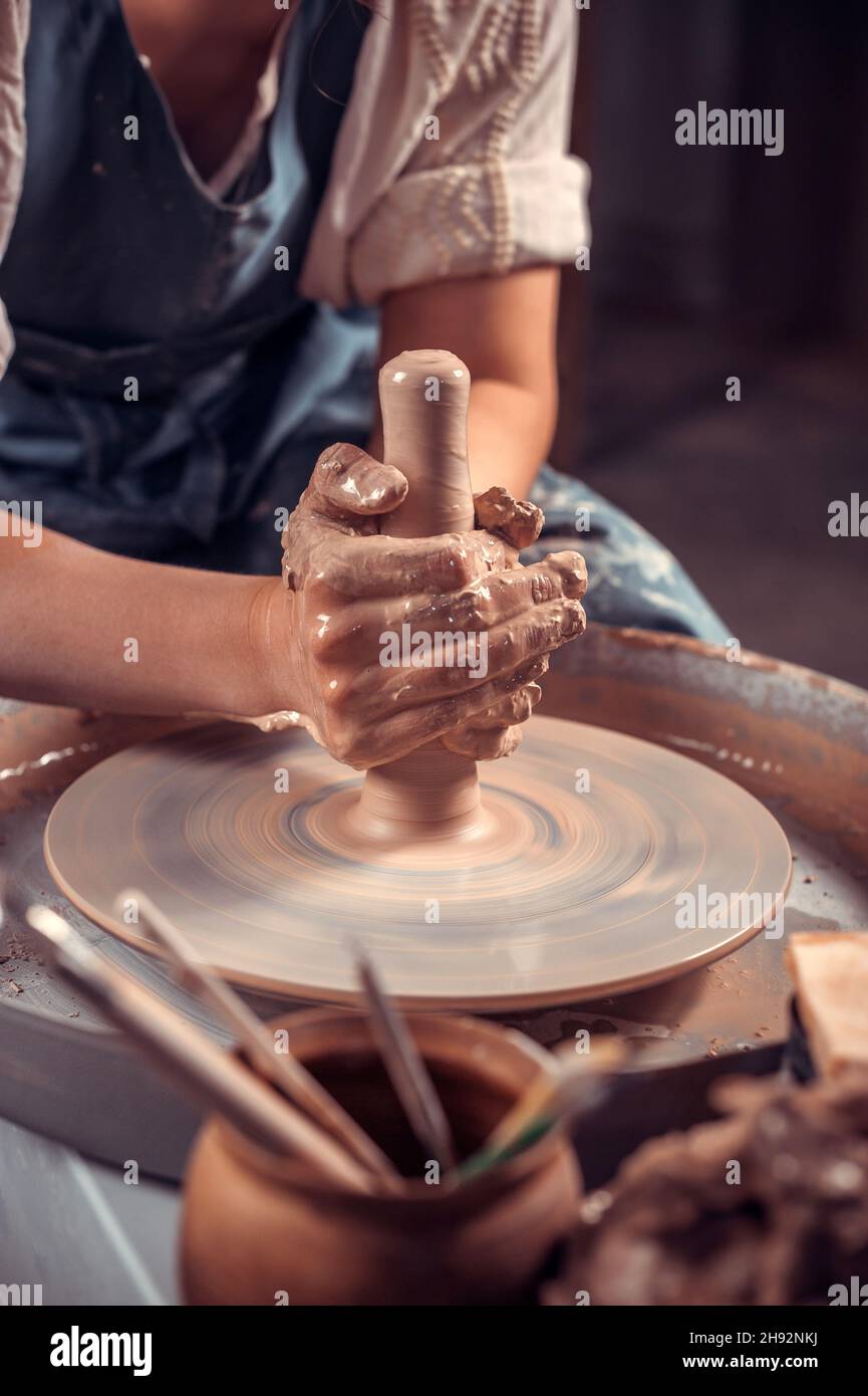 Hands of the master potter and vase of clay on the potter's wheel close ...