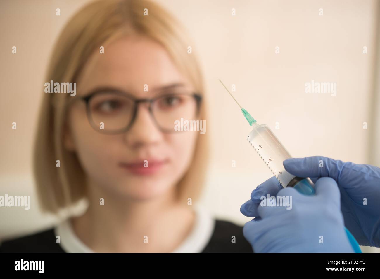 Fear of injections. Frightened girl looks at syringe needle during ...