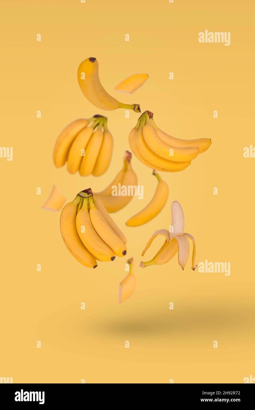 Lots fresh bananas flying in air isolated on a pastel yellow background ...
