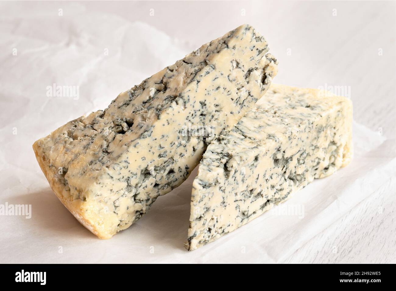 Two blue cheese wedges on white wax paper Stock Photo - Alamy