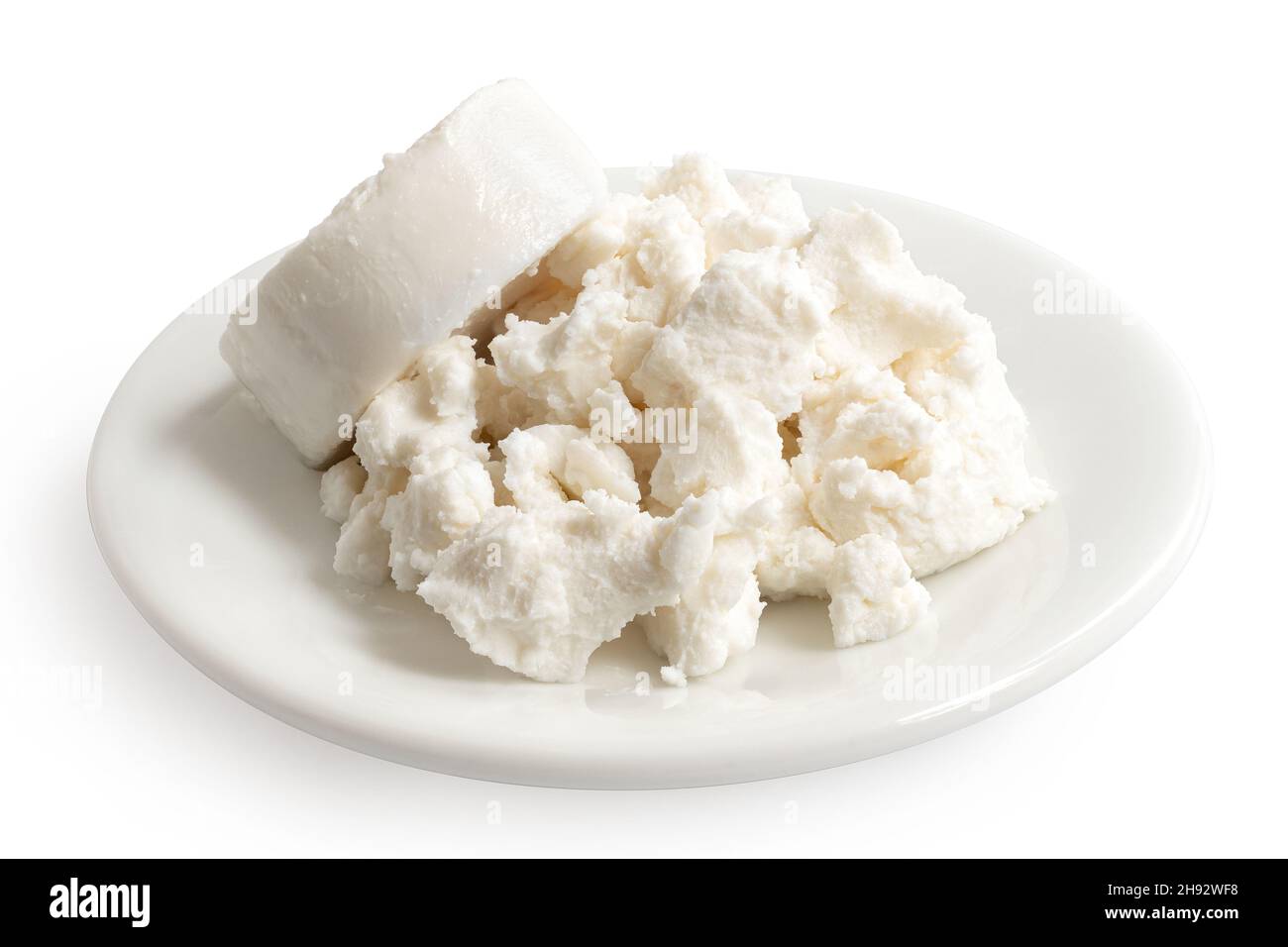 Round of goat cheese and crumbled goat cheese on white ceramic plate ...