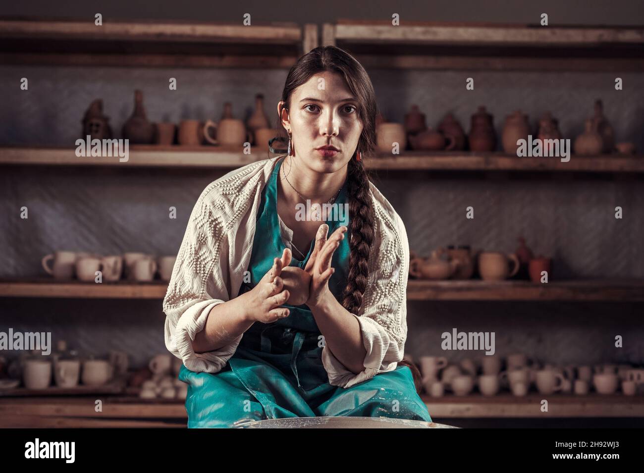 Hands of the master potter and vase of clay on the potter's wheel close ...