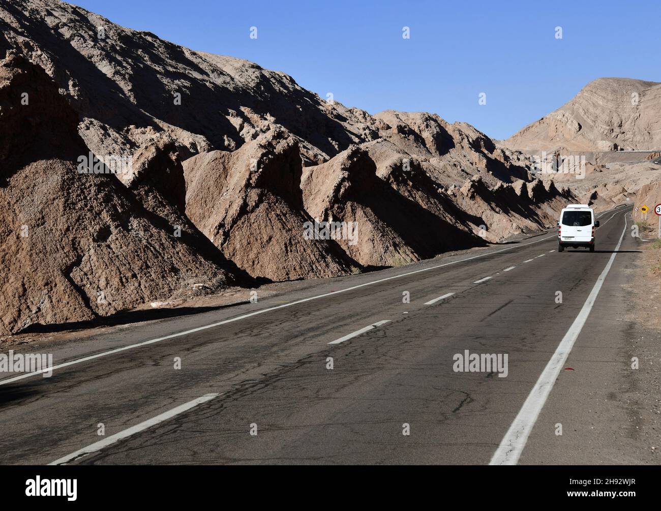 Minibus driving on the road along the rocks in the deserted area of the ...