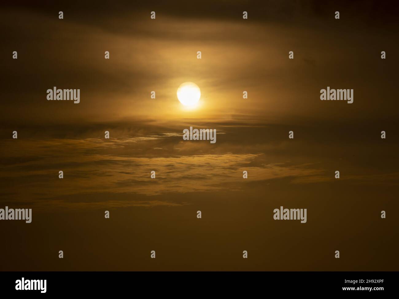 Sun rising through clouds Stock Photo - Alamy