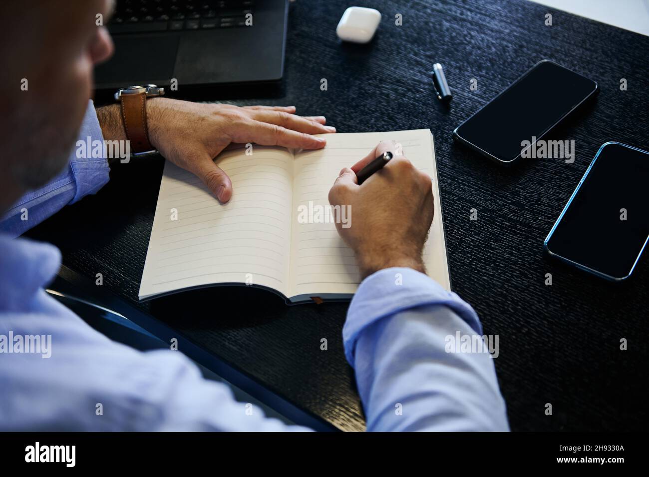 Overhead view of a man writing in a notebook with empty blank paper ...