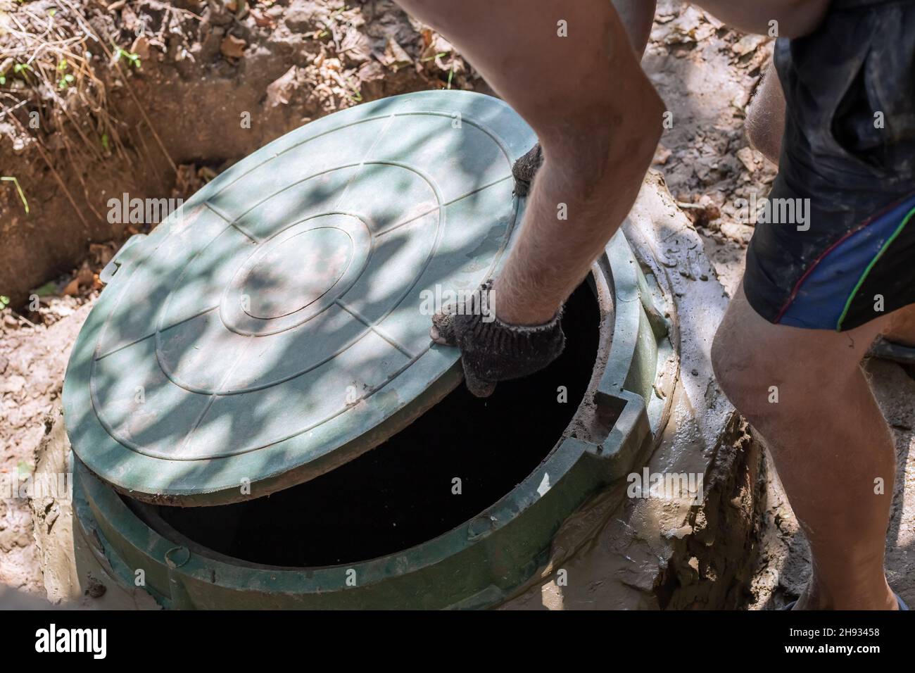 The man opens the sewer hatch. Installation and maintenance of septic ...