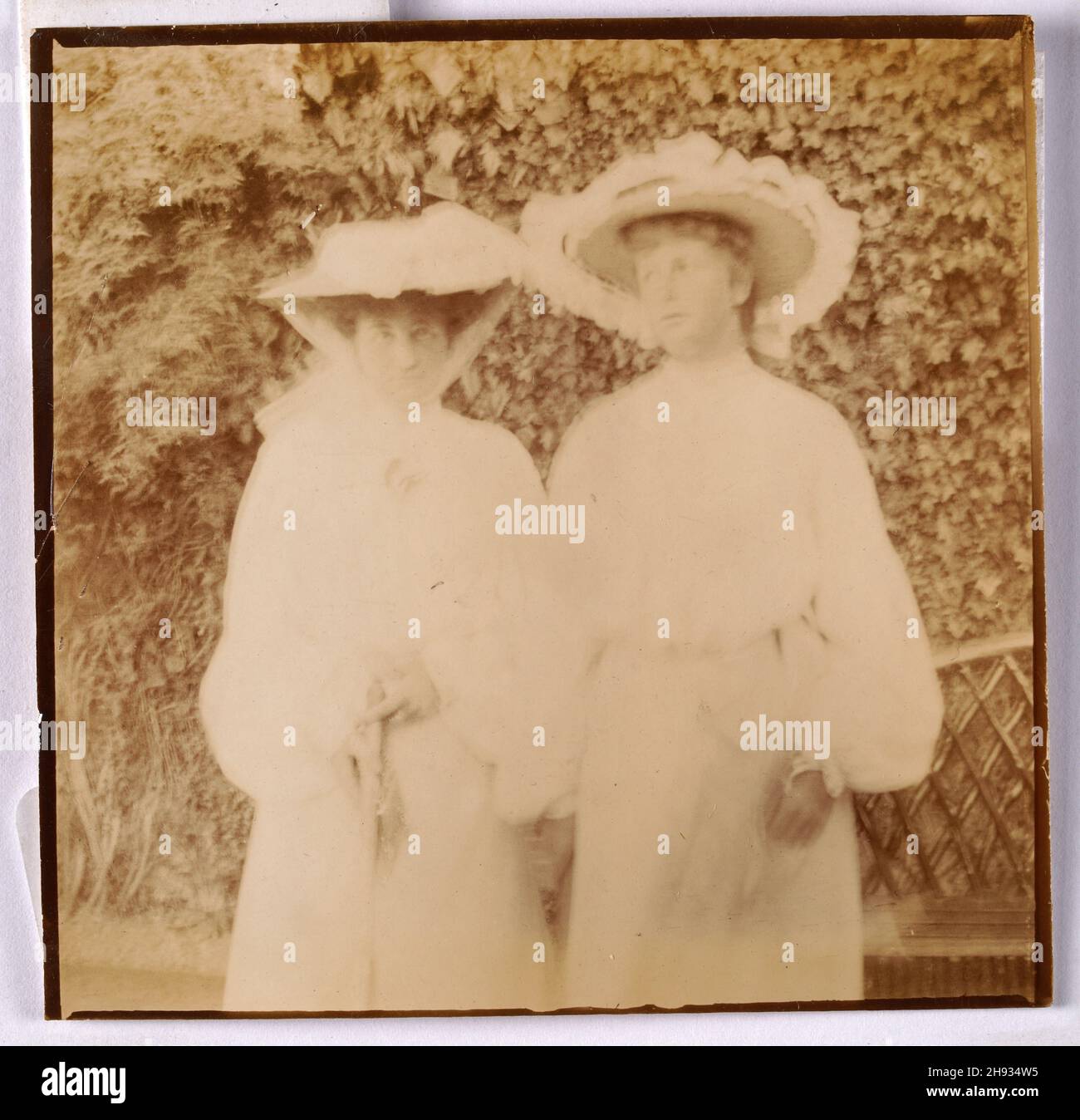 Vintage faded out of focus photograph of two women in white dresses ...