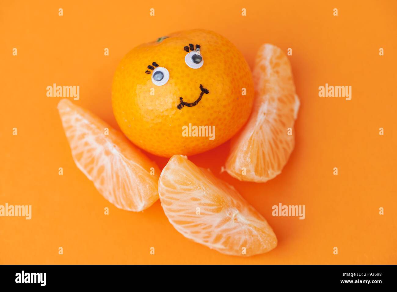tangerine with a face on orange background Stock Photo - Alamy