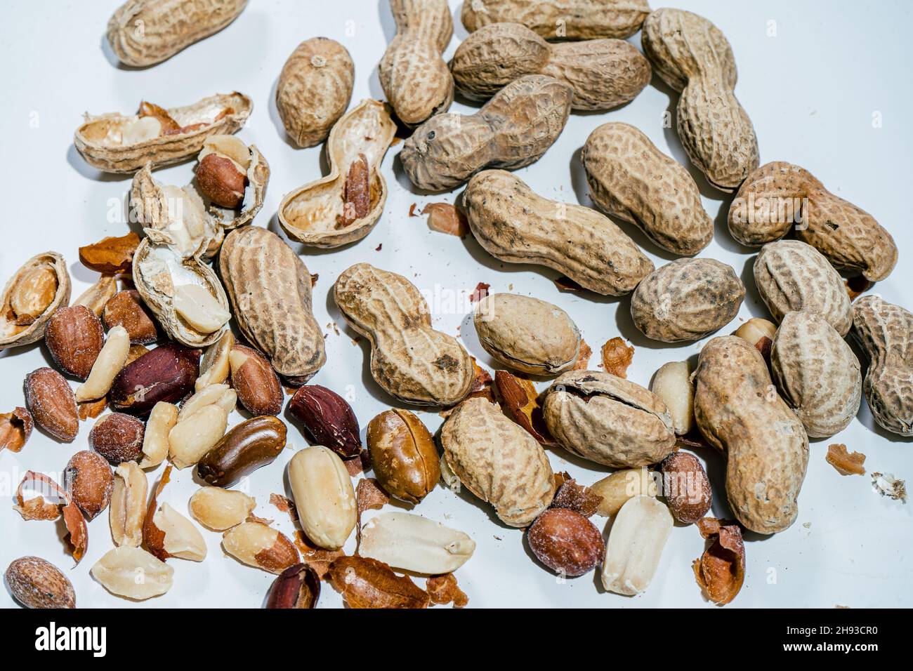 A peeled peanuts and in their shell on a white surface Stock Photo - Alamy
