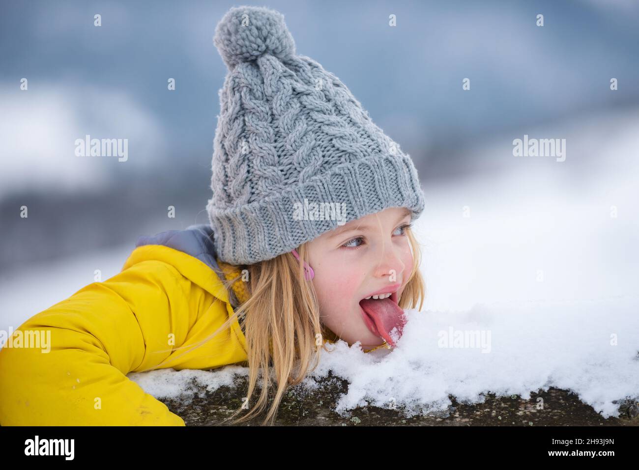 Funny little girl walking eating snow on winter day. Excited christmas ...