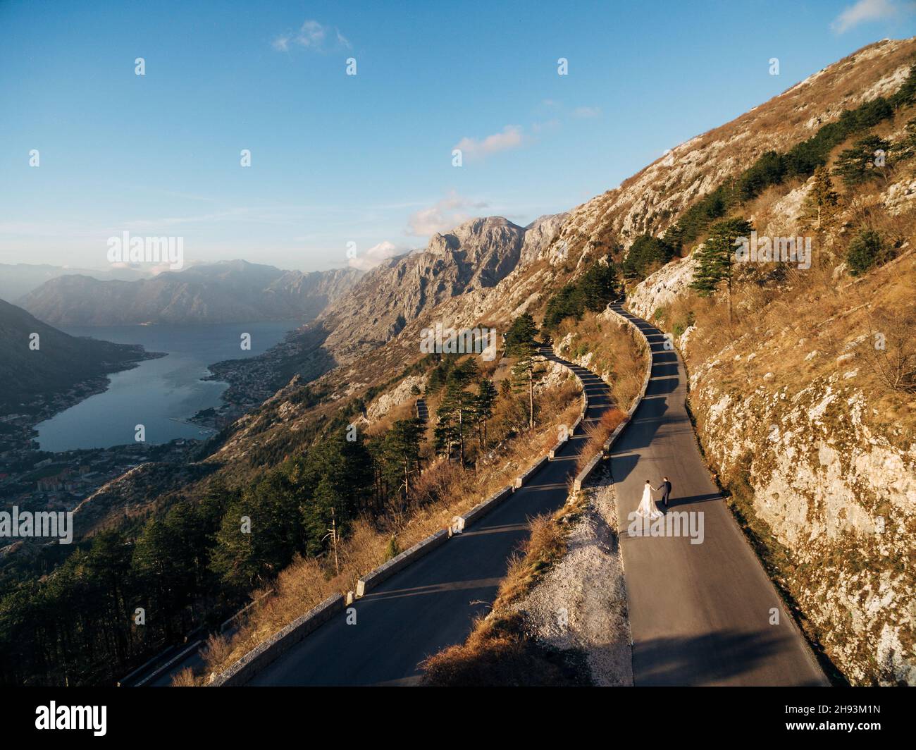 Bride and groom walk along the mountain serpentine against the backdrop ...