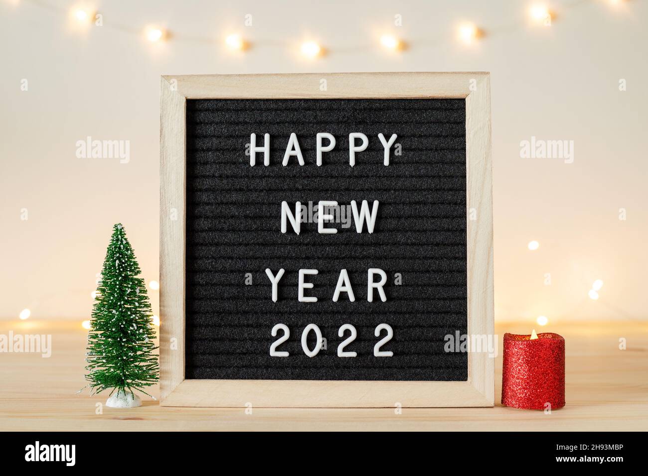 Happy new year 2022 greetings on letter board on table with small ...