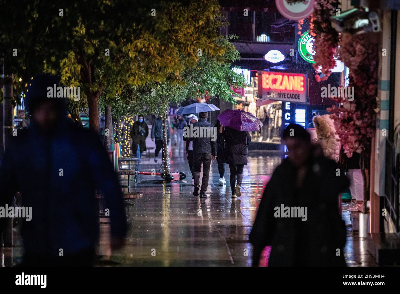 People shelter from the rain beneath umbrellas along Bahariye Street in ...