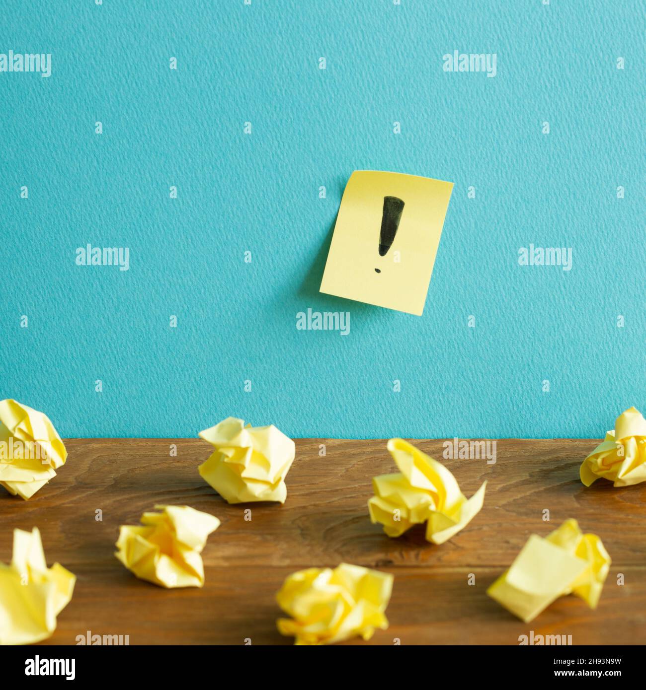 Crumpled paper balls and notepad with exclamation mark on wooden desk ...