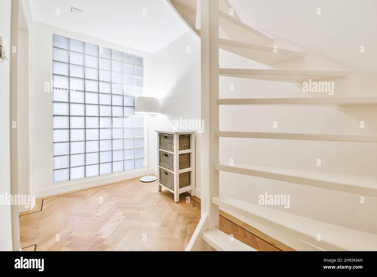 White hallway with wooden stairway leading to second floor of modern ...