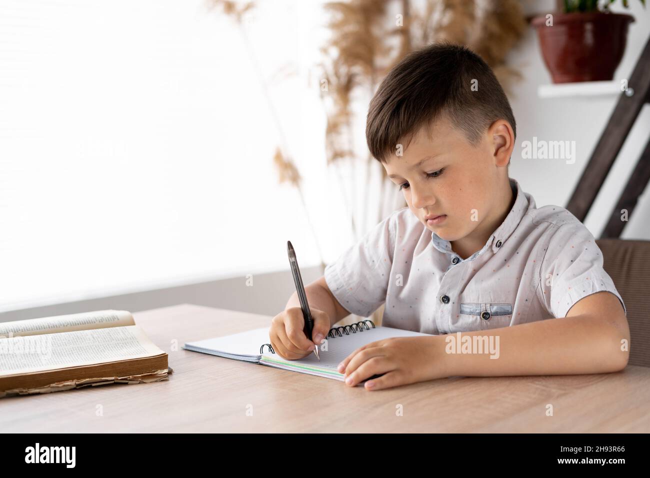 serious male student doing handwritten homework in a notebook while ...