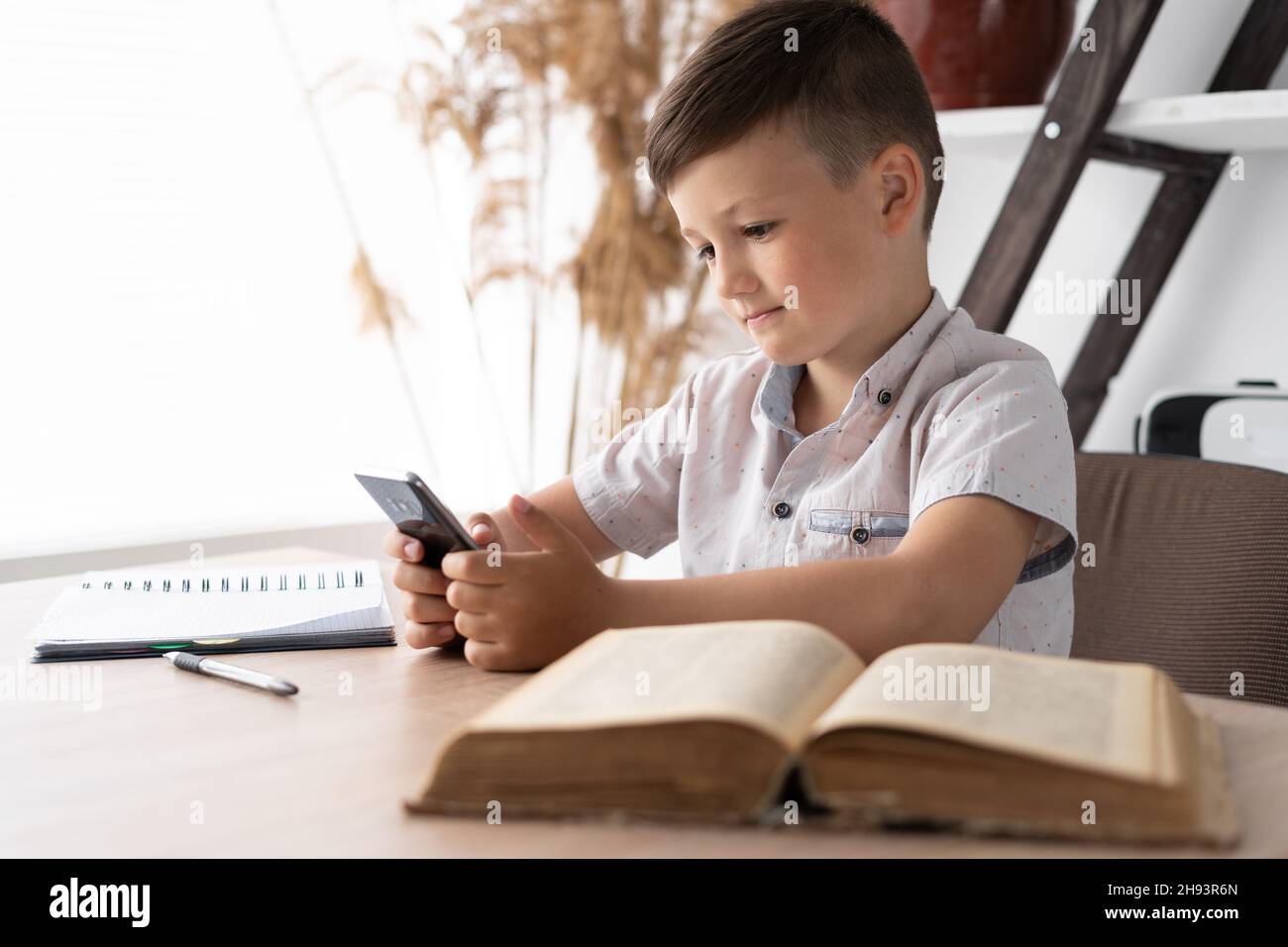 concentrated boy playing a game on the mobile phone while sitting at ...