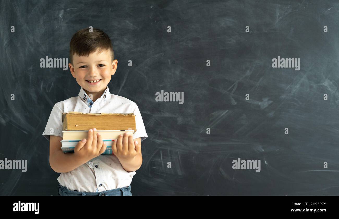 Happy college student standing by the chalk board in the classroom with ...
