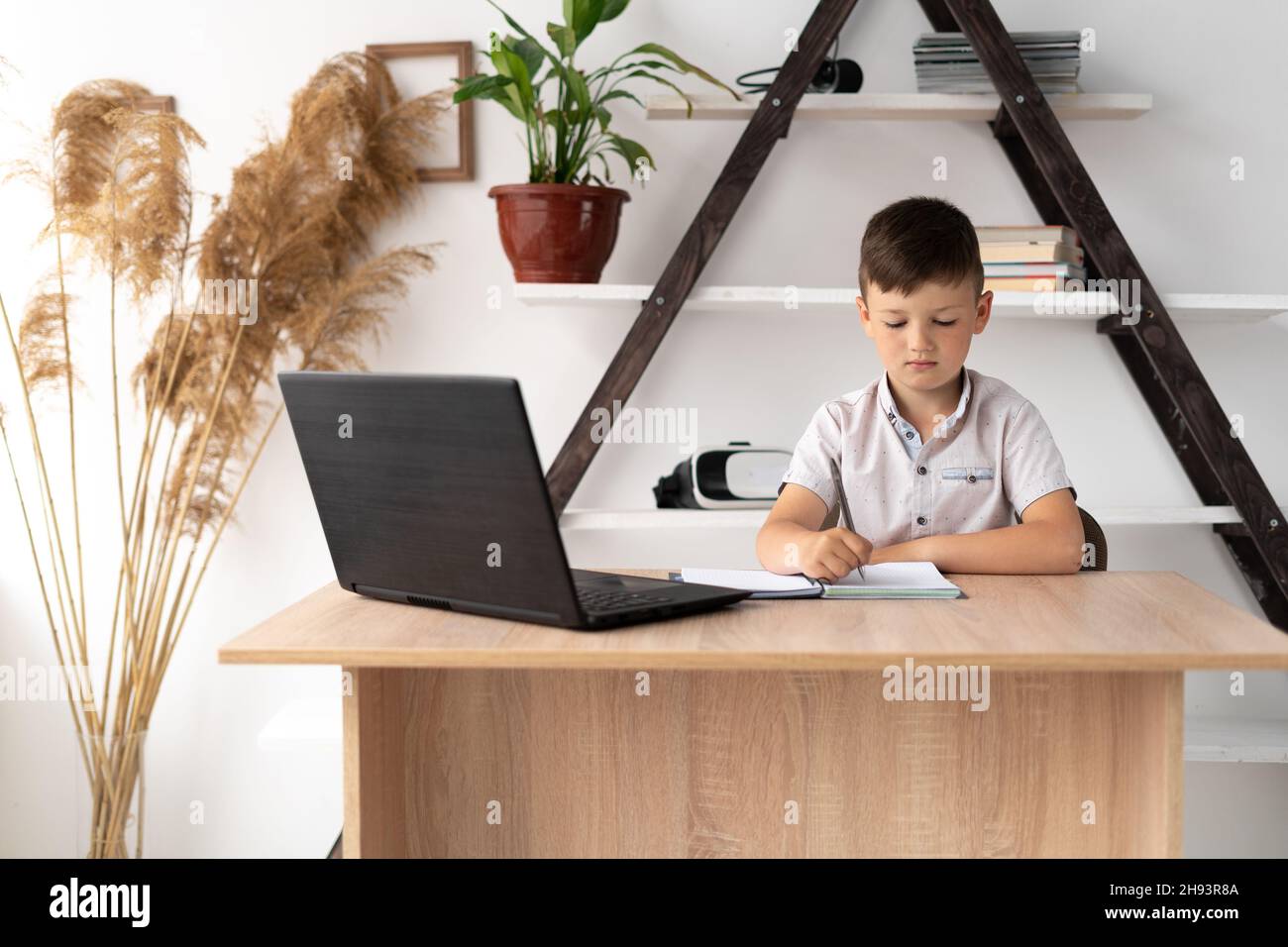 Homeschooling online boy doing homework using a laptop listening to a ...