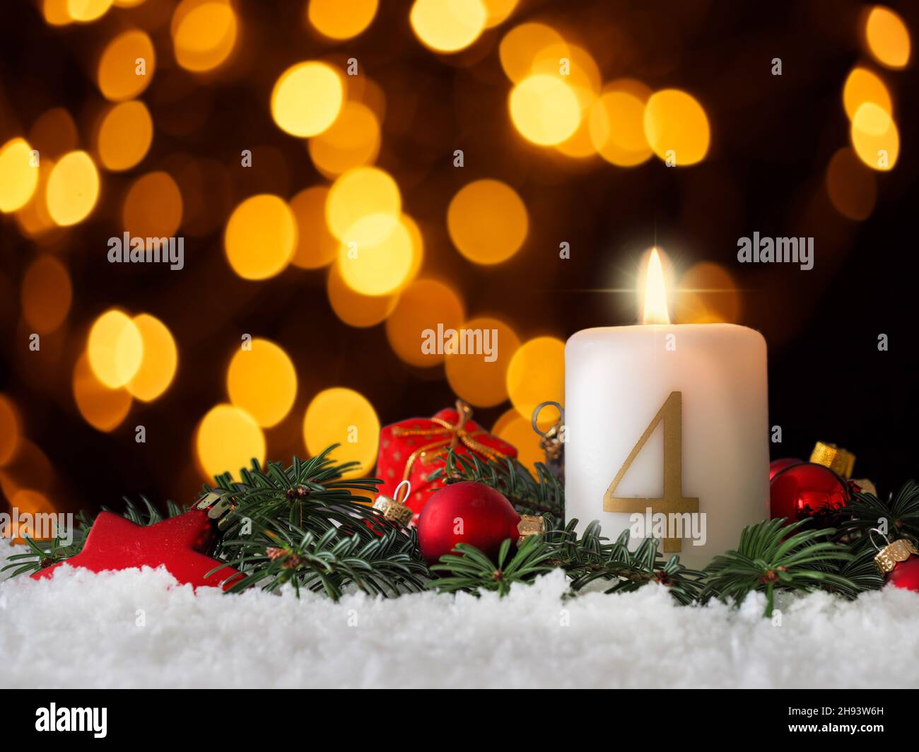 Candle of the fourth Advent burns, fir branches and Christmas tree ...