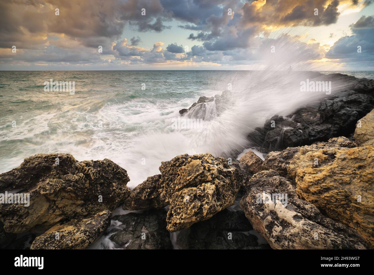Beautiful seascape. Sea waves during storm on sunset splash on stones ...
