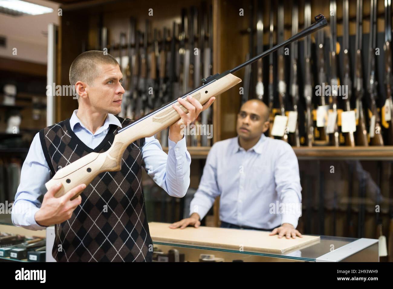 Two adult men choosing pneumatic weapon in military store Stock Photo ...