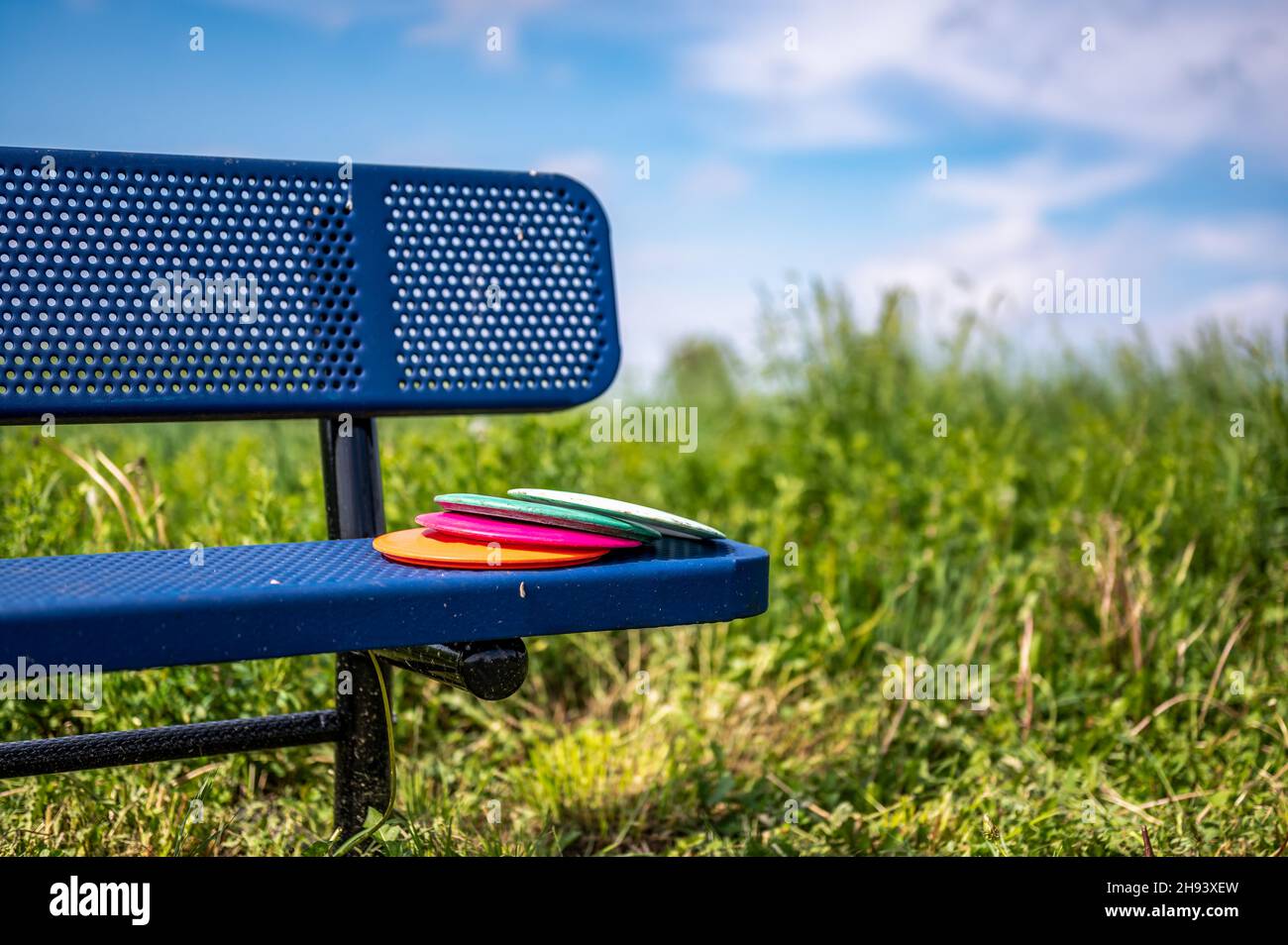 Pile of discs resting on a bench in the golf course park Stock Photo ...