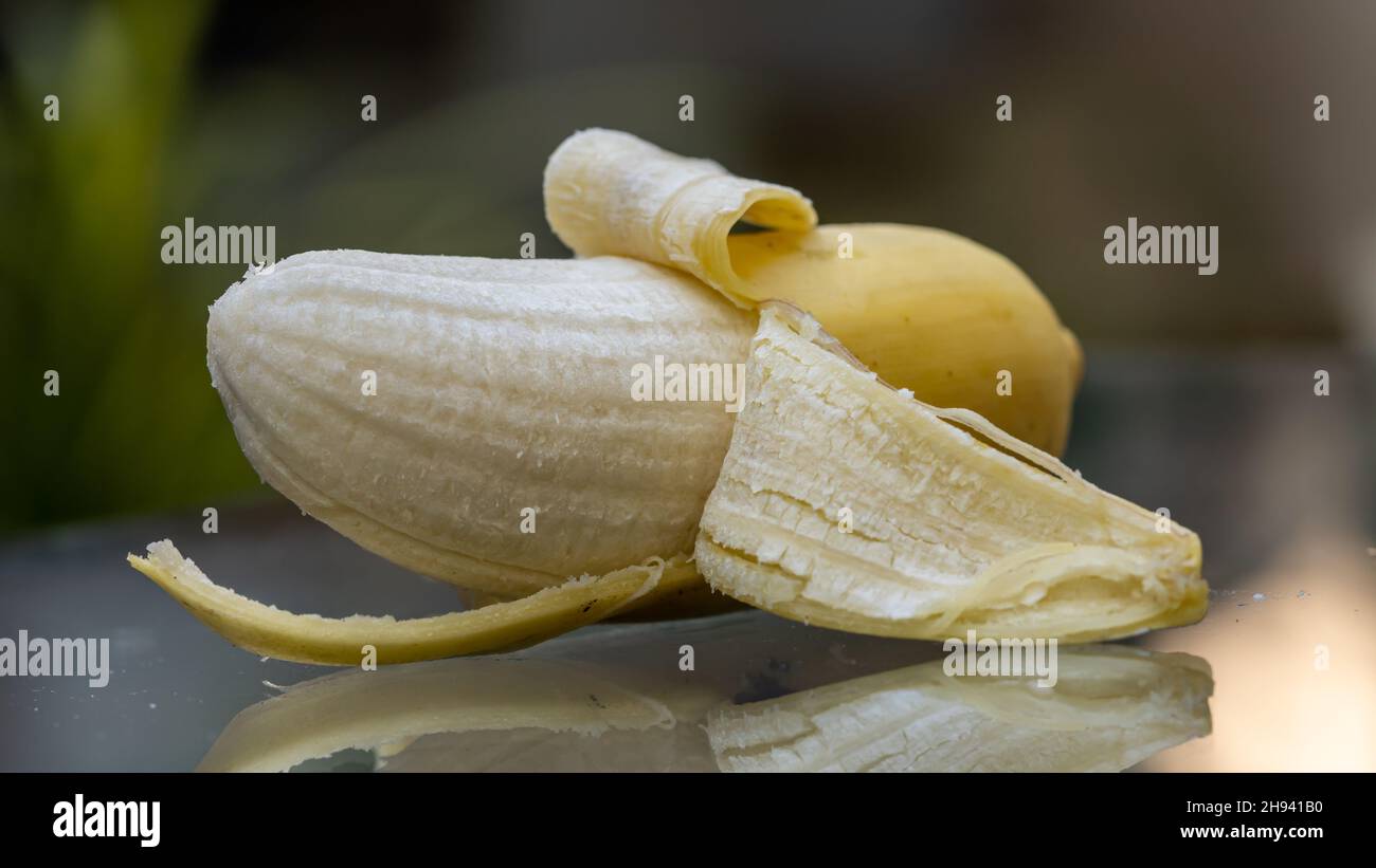 Half peeled Banana with shadow on the glass, Open Banana isolated on a ...