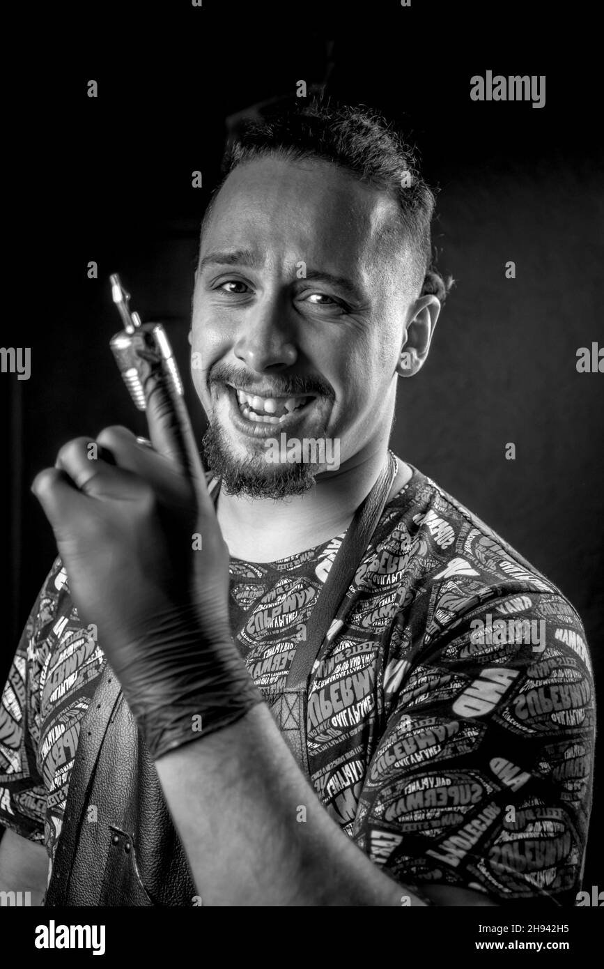 Master of the art of tattooing with a tattoo gun in a tattoo studio ...