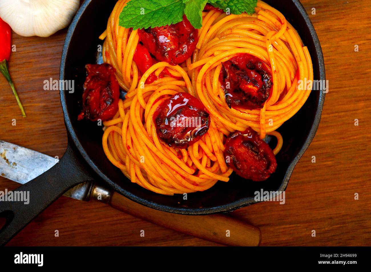 italian spaghetti pasta and tomato with mint leaves on iron skillet ...