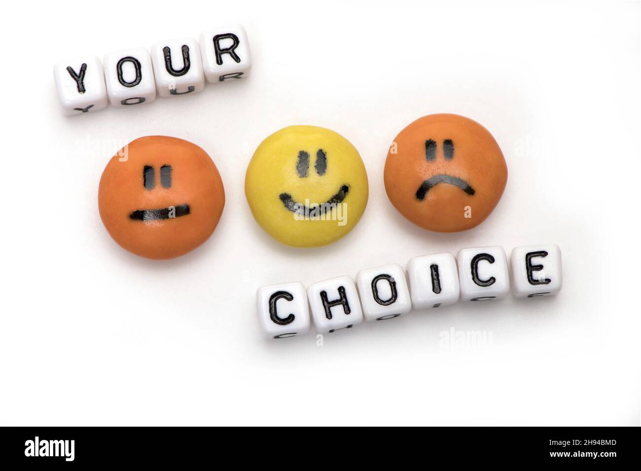 two orange and one yellow round candy with faces on them representing ...