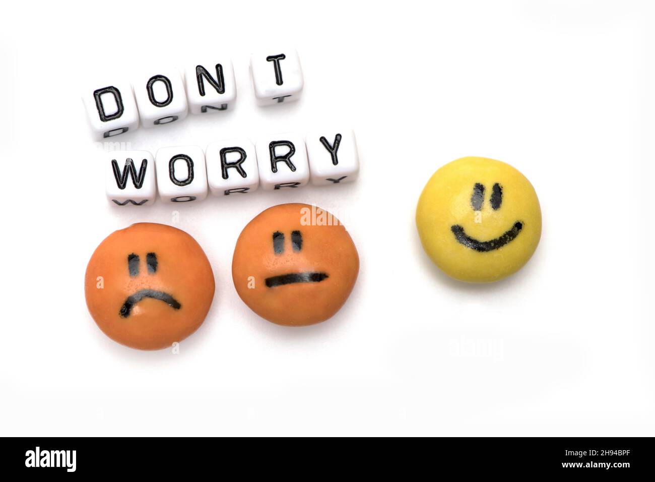 two orange and one yellow round candy with faces on them representing ...