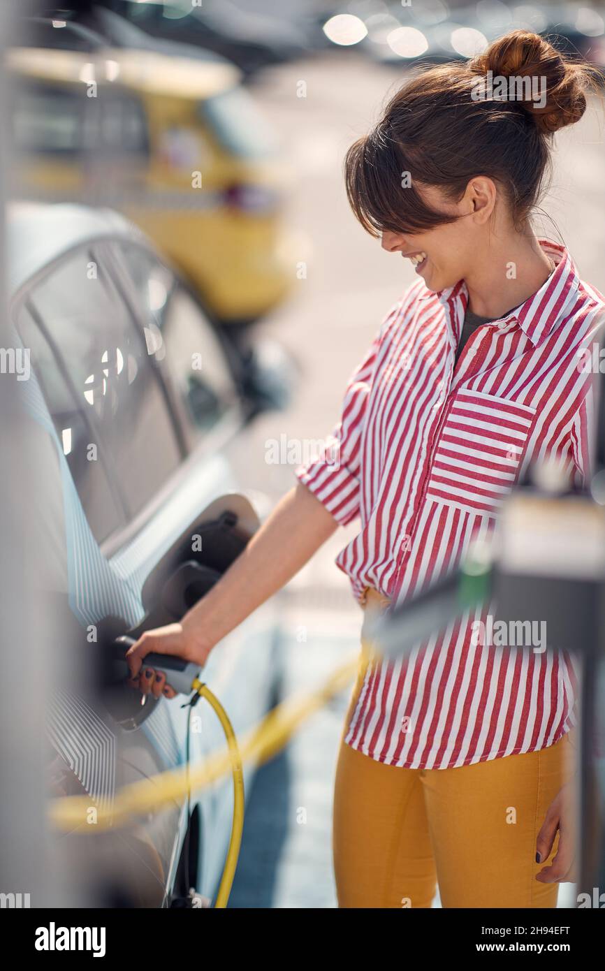 Caucasian woman charging her electric car at the charging station Stock ...