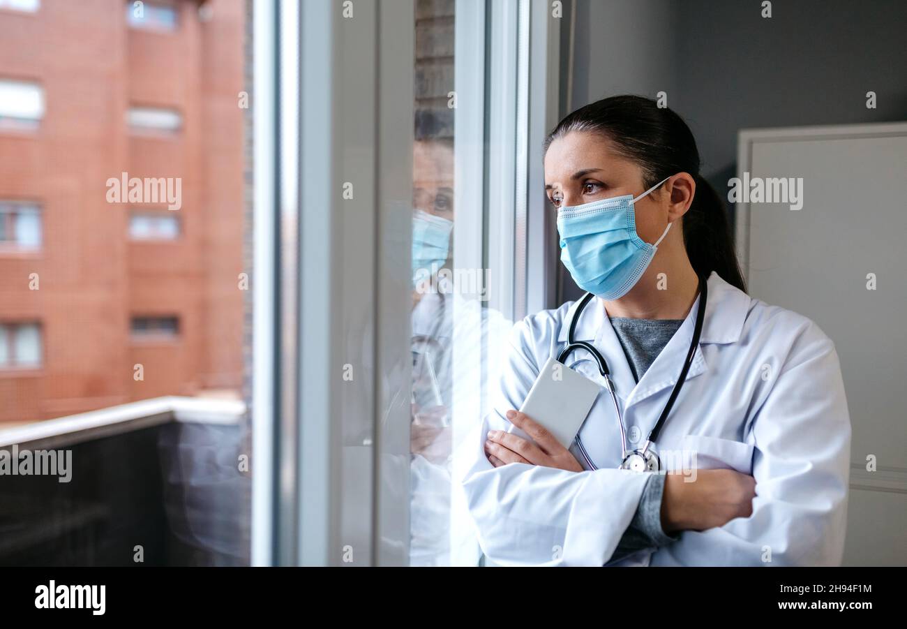 Female doctor looking out the hospital window Stock Photo - Alamy