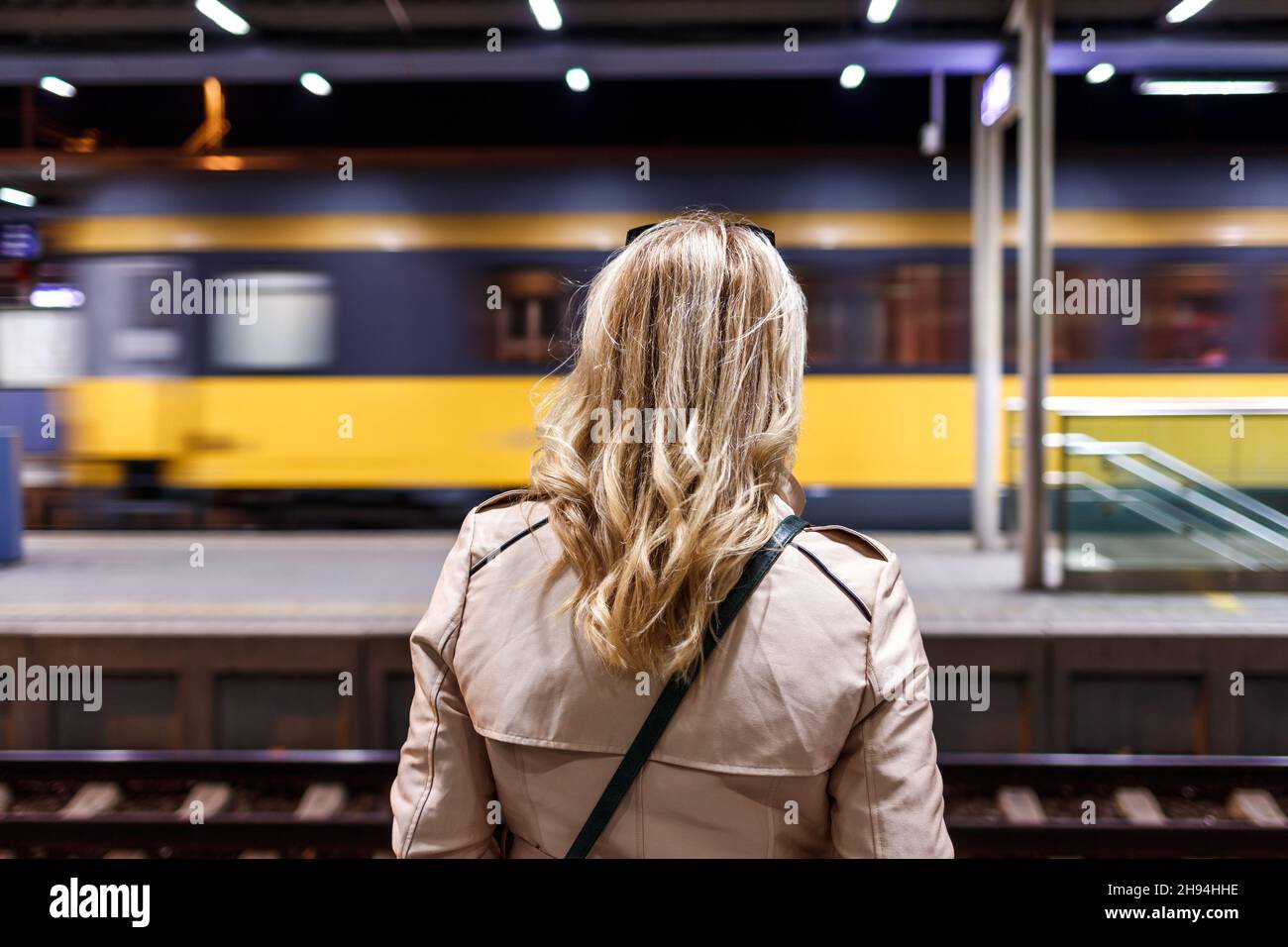 Woman looking at passing train at railroad station. Public ...