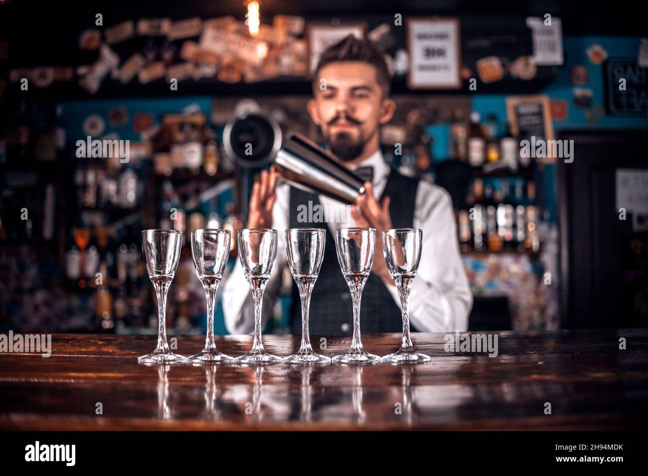 Charming bartender adds ingredients to a cocktail in the nightclub ...