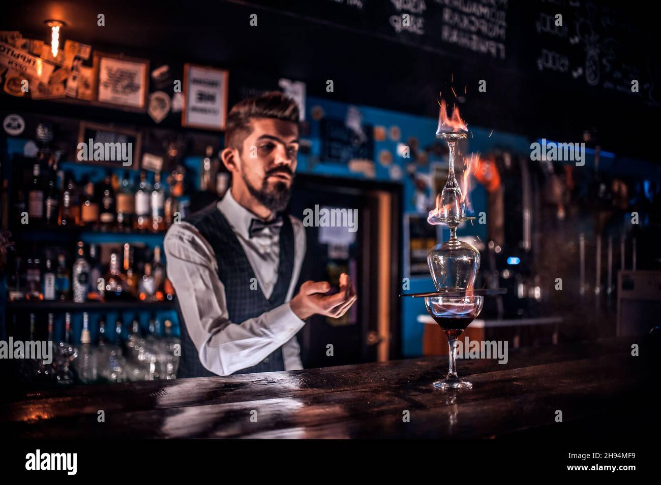 Charming barman demonstrates the process of making a cocktail behind ...