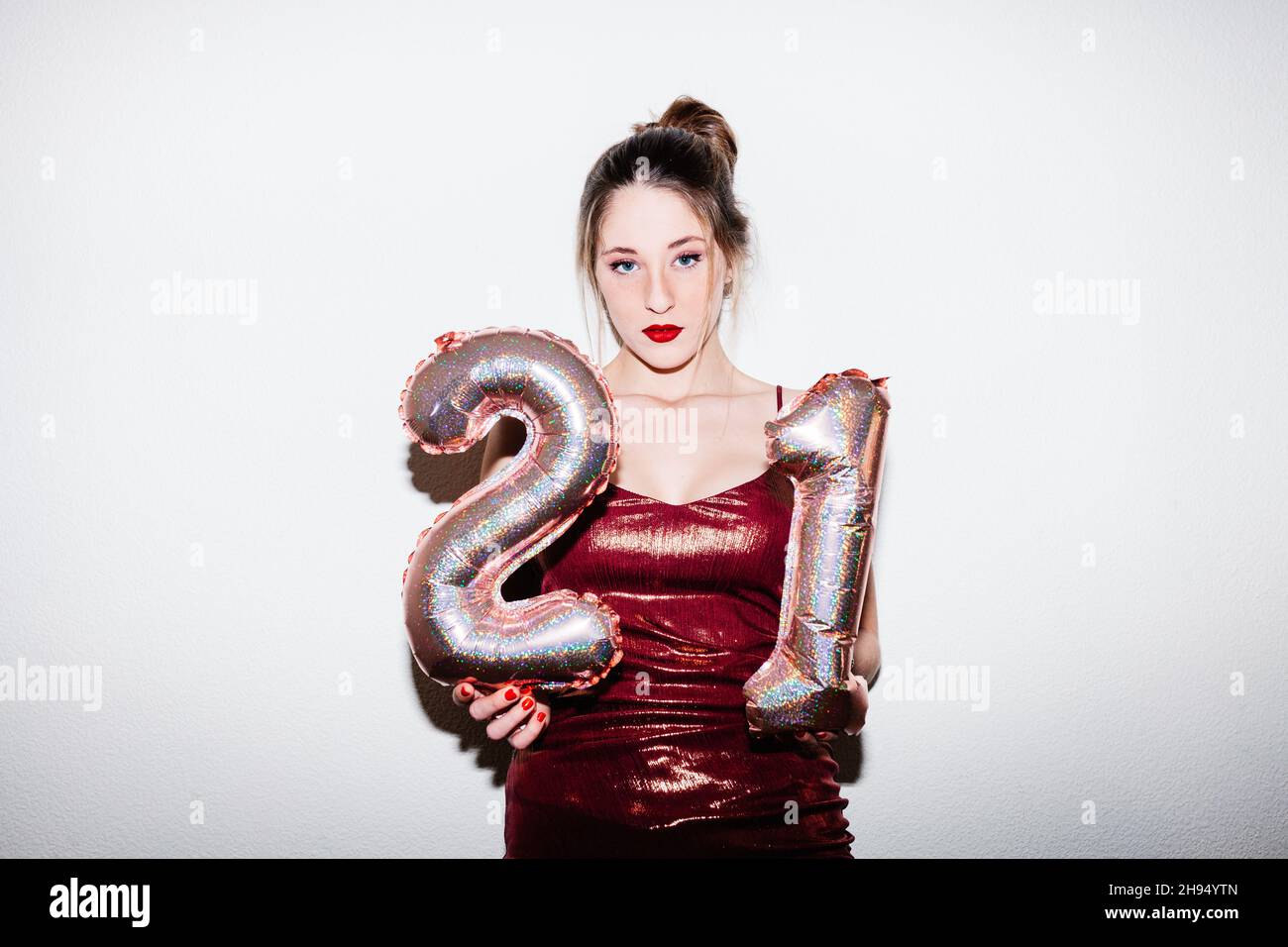 Young woman celebrating her 21st birthday illuminated with hard flash ...