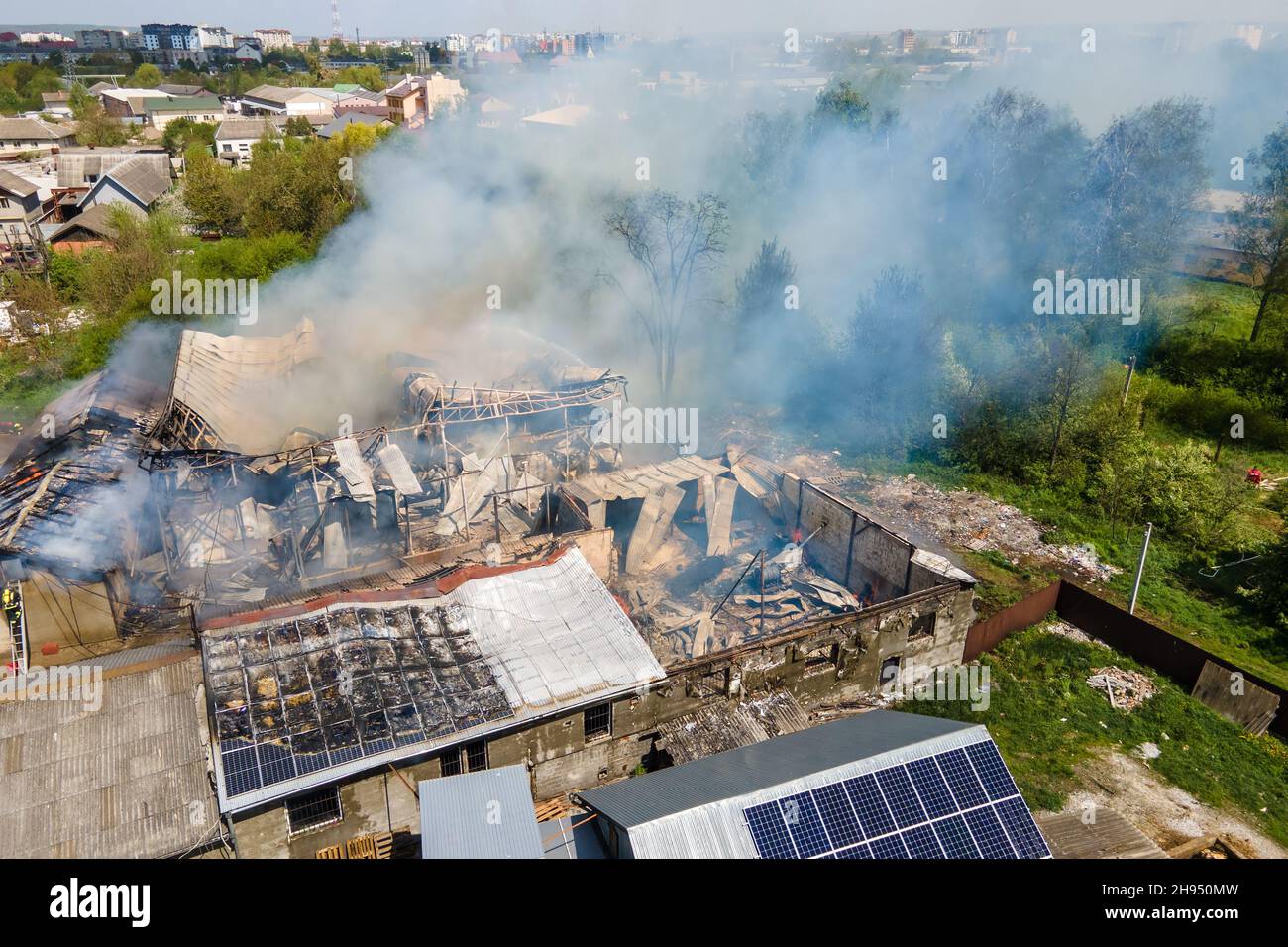 Aerial view of ruined building on fire with collapsed roof and rising ...