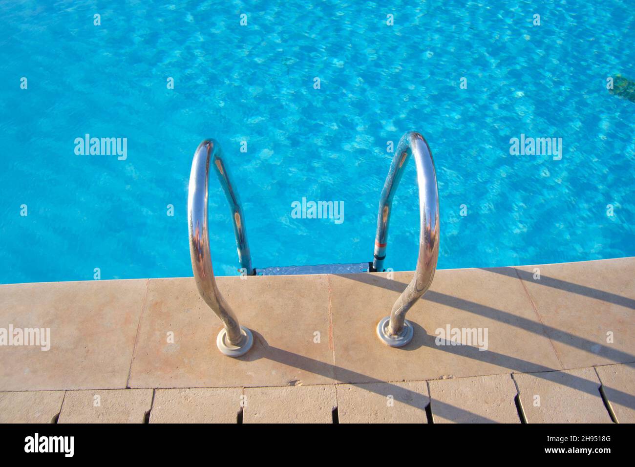 Close up of swimming pool stainless steel handrail descending into ...