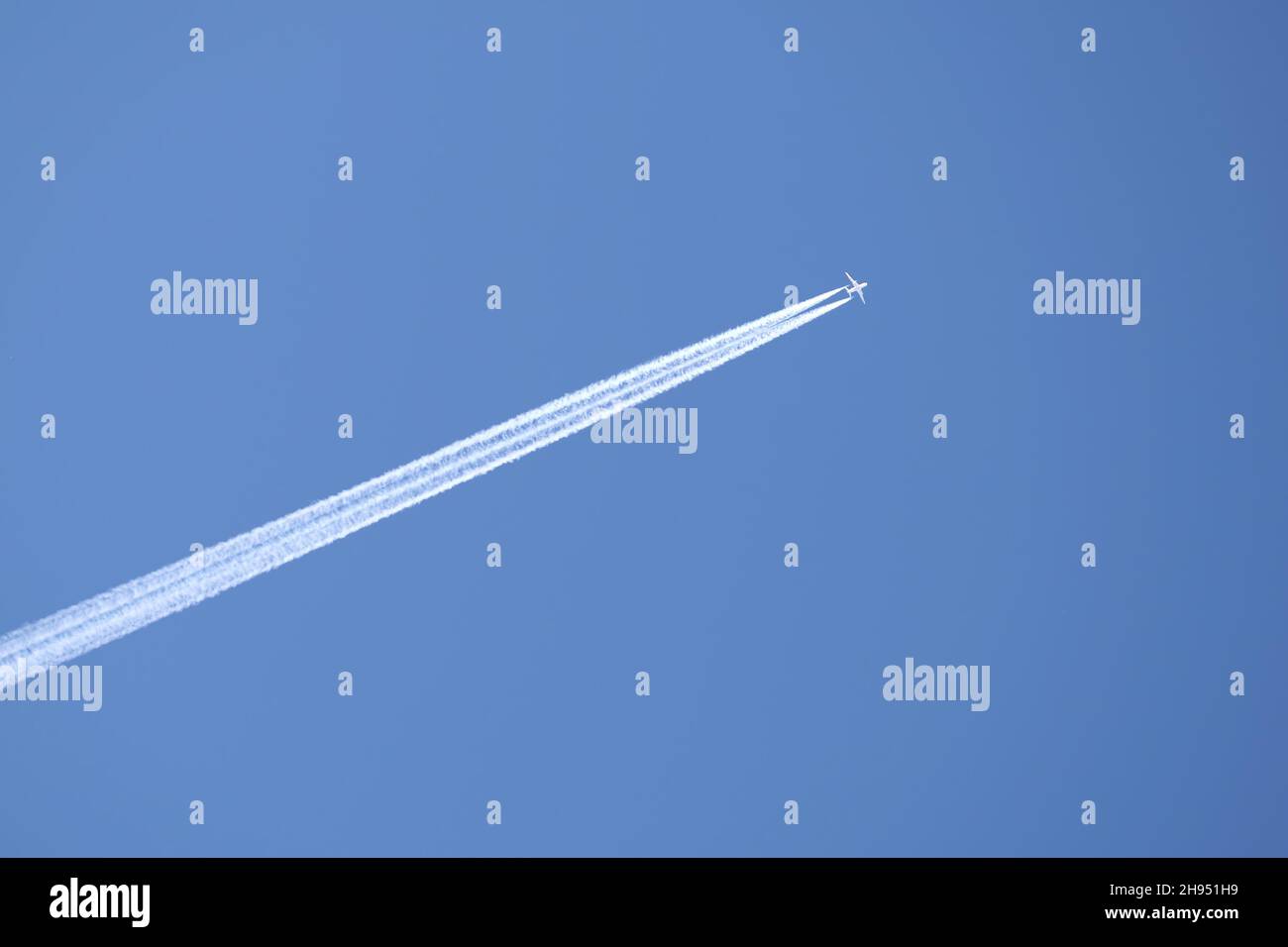 Distant passenger jet plane flying on high altitude on clear blue sky ...