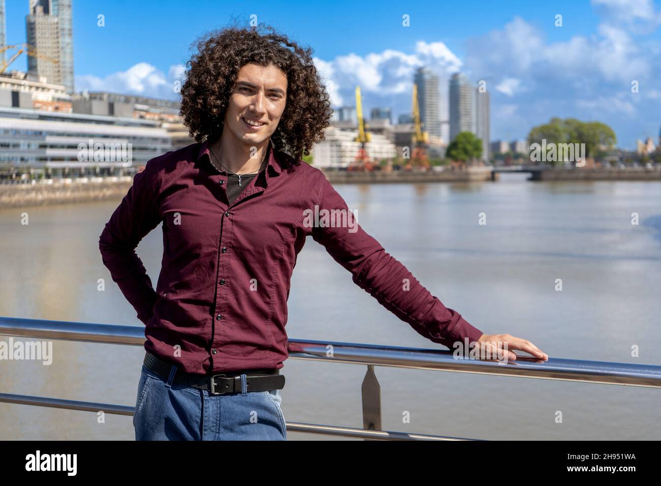 A portrait of a smiling man leaning on the railing in the harbor with ...