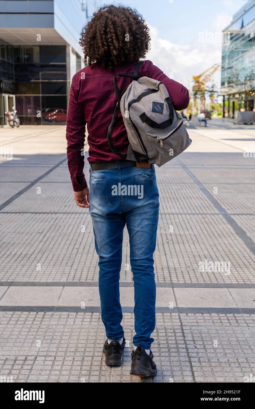 A full-length portrait from behind of a young man with a backpack ...