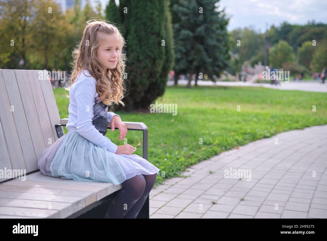 Portrait of pretty child girl sitting on park bench outdoors Stock ...