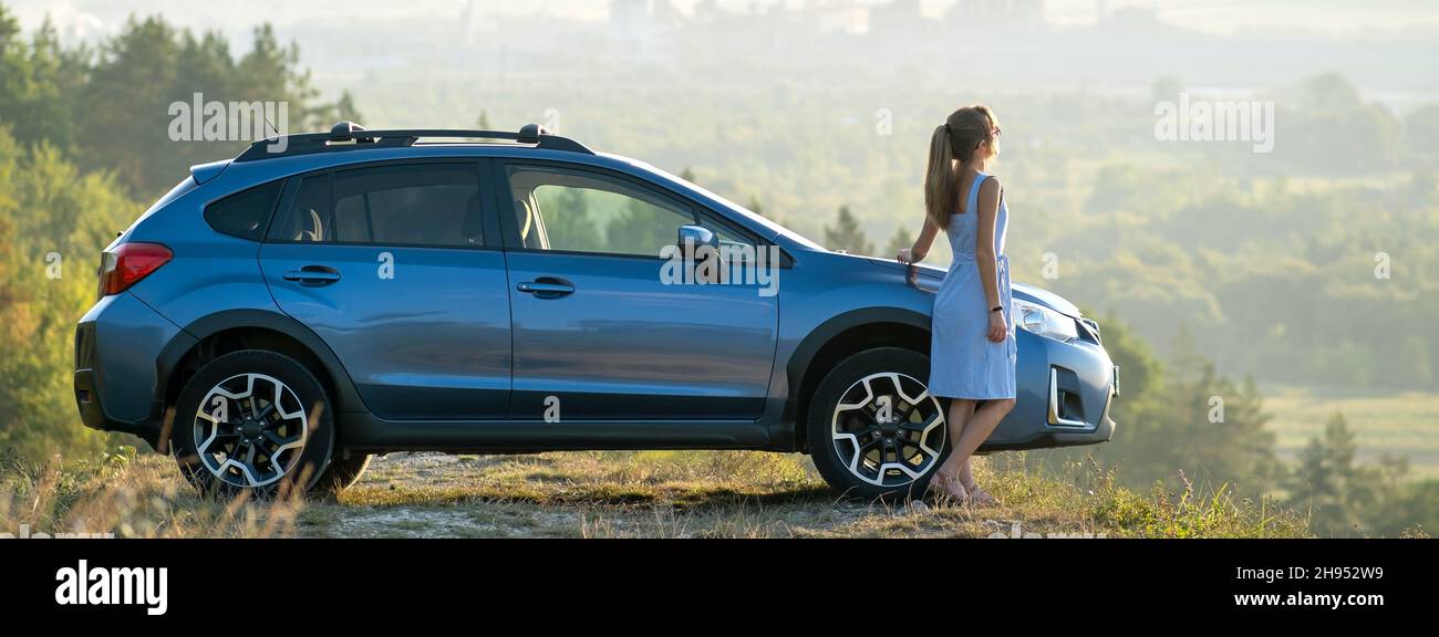 Young female driver resting near her car enjoying warm summer evening ...