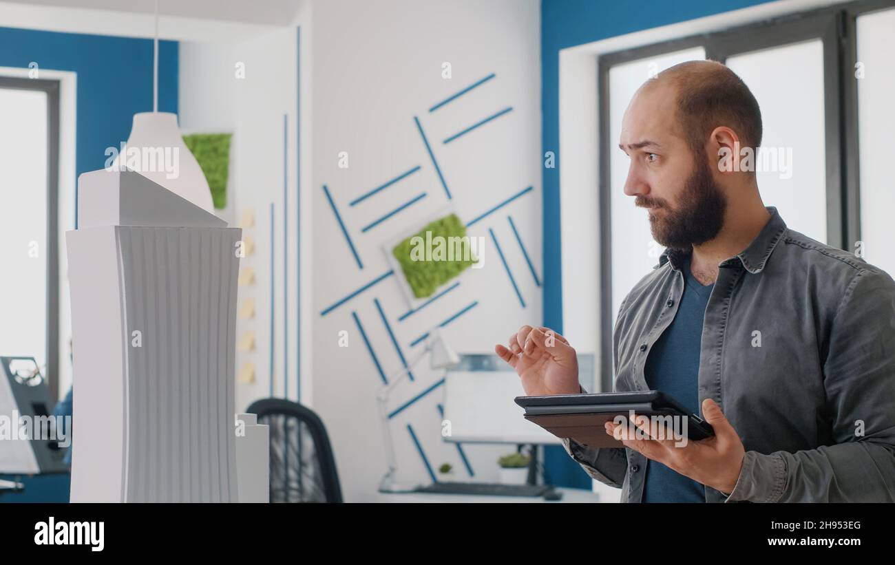 Close up of architect using digital tablet and building model to work ...