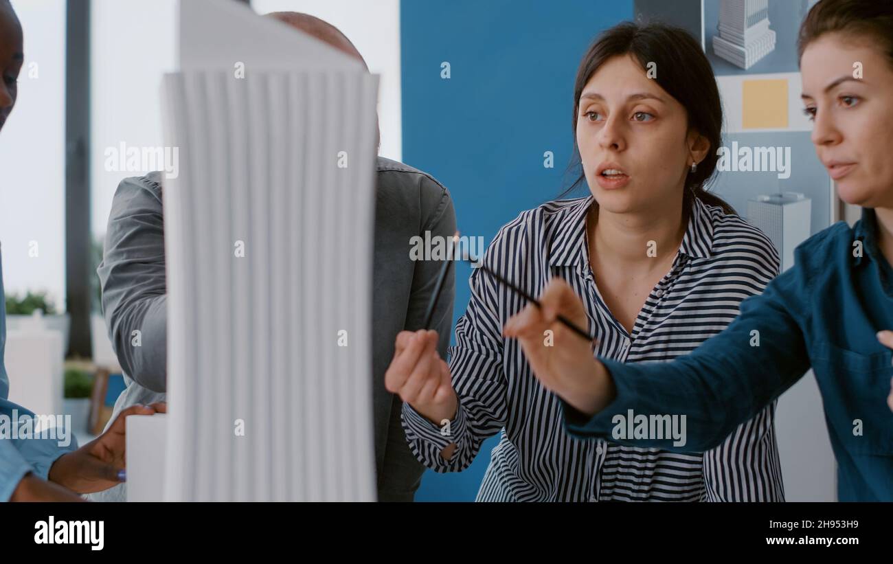 Close up of people looking at building model on table to plan ...