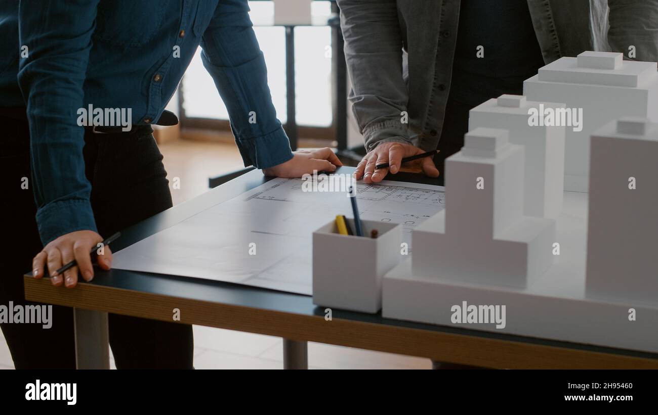 Close up of colleagues working on urban design with blueprints and ...
